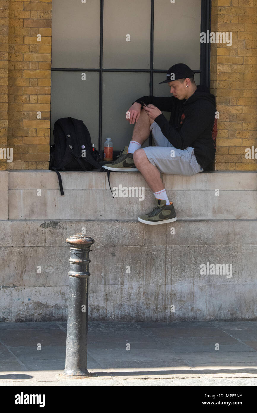 man sitting on window ledge sill using a smartphone or portable device ...