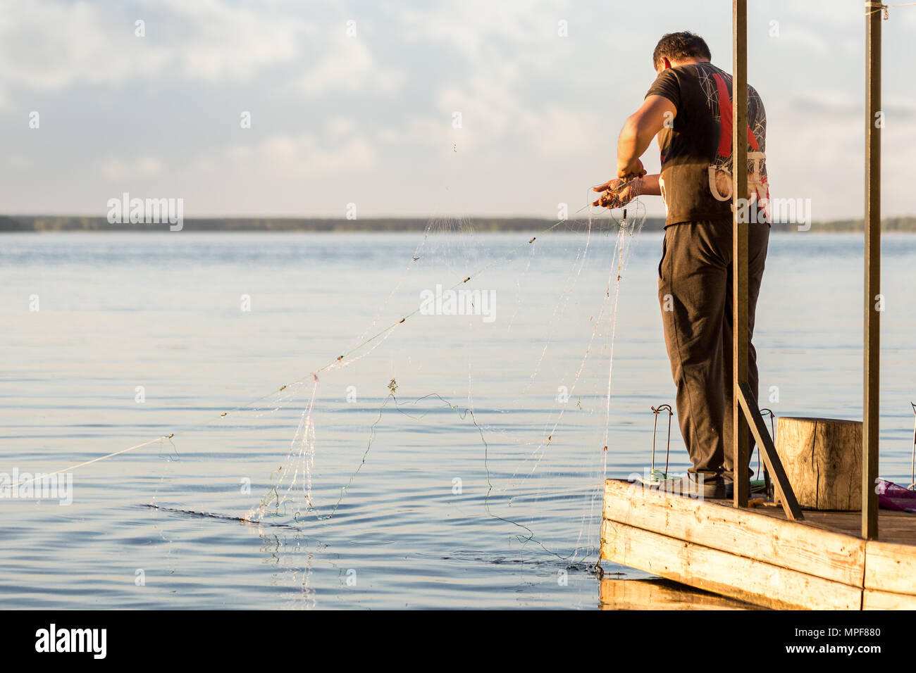 Fisherman on wooden pierce. Fishing man taking out net from water ...