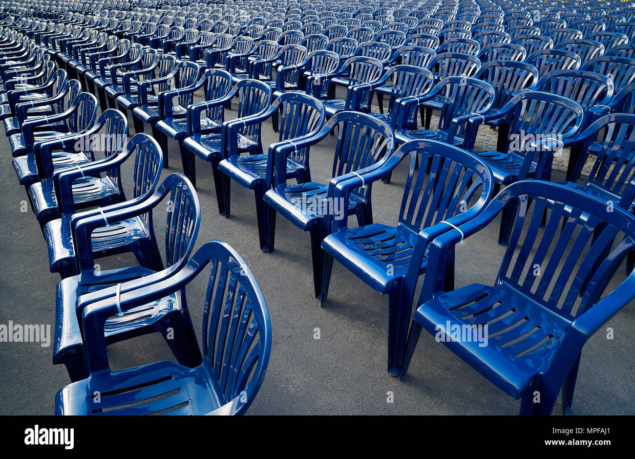 Plastic hire chairs in a row blue color tied with zip Stock Photo - Alamy