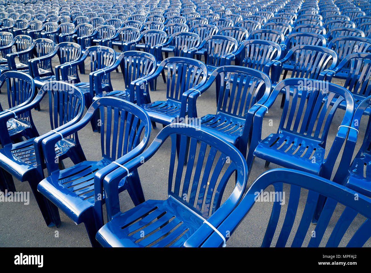 Plastic hire chairs in a row blue color tied with zip Stock Photo - Alamy