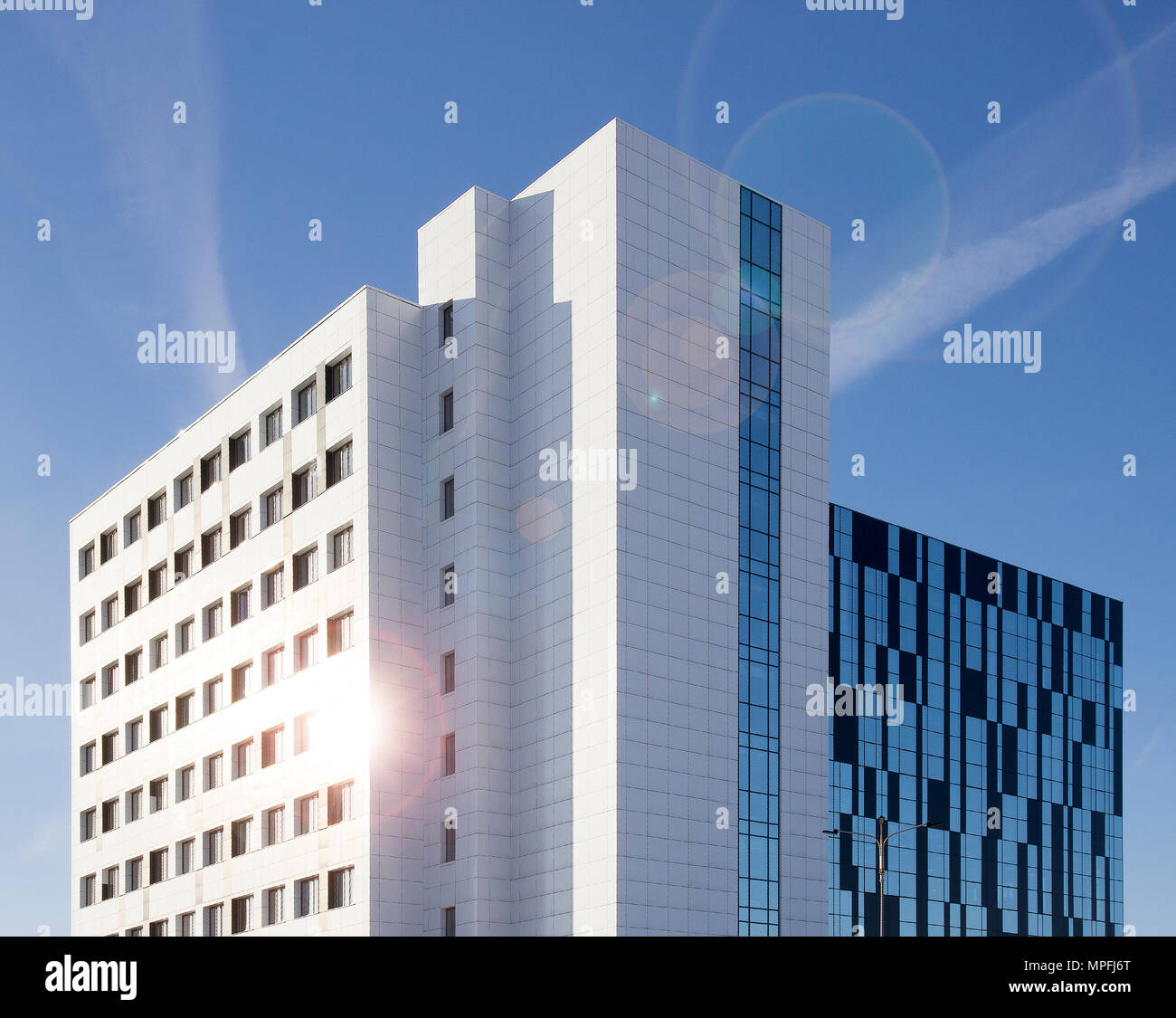 Skyscraper with sunlight flare in glass window against clear blue sky ...