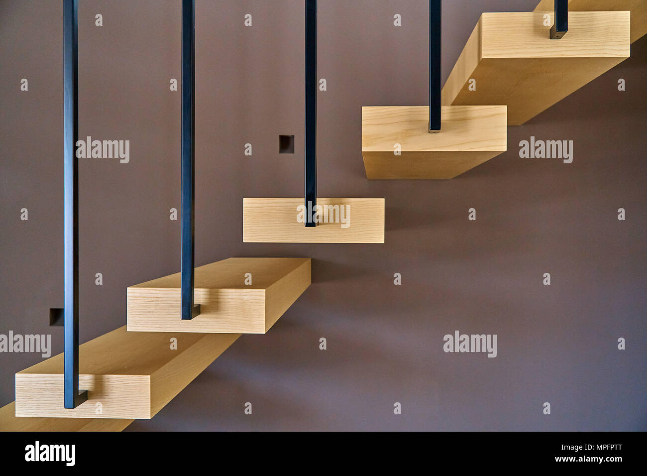 Floating stairs. Ash lumber stairs with metal railing attached to brown ...