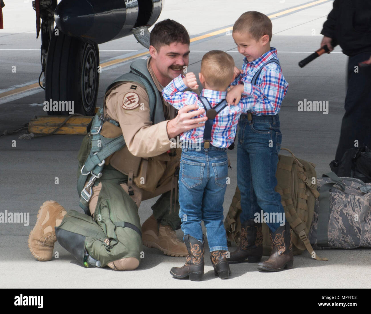 Two boys laugh with excitement over their fathers return from a six ...