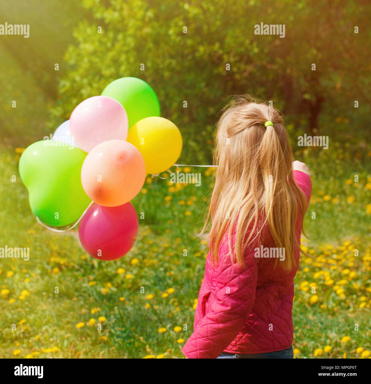 Outdoor portrait of a cute young little girl Turned back with balloons ...