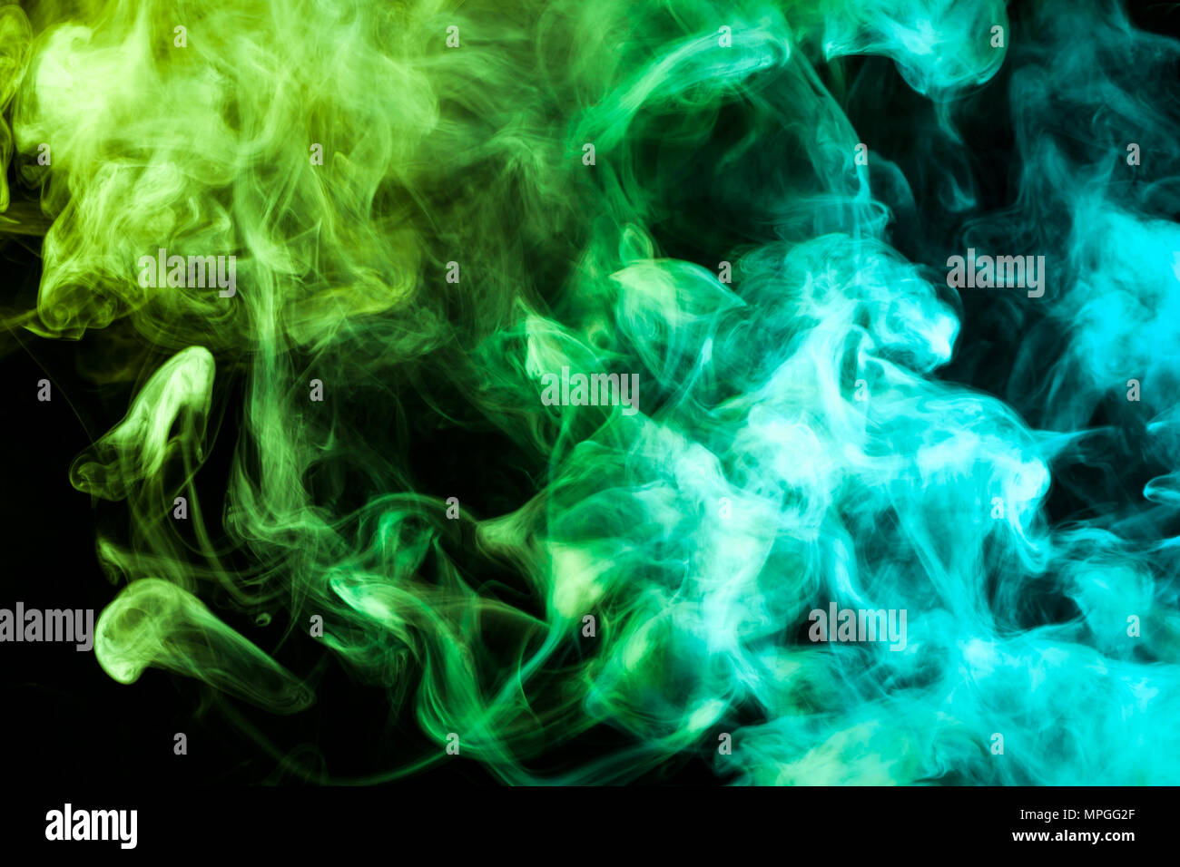 Dense multicolored smoke of green and blue colors on a black isolated ...
