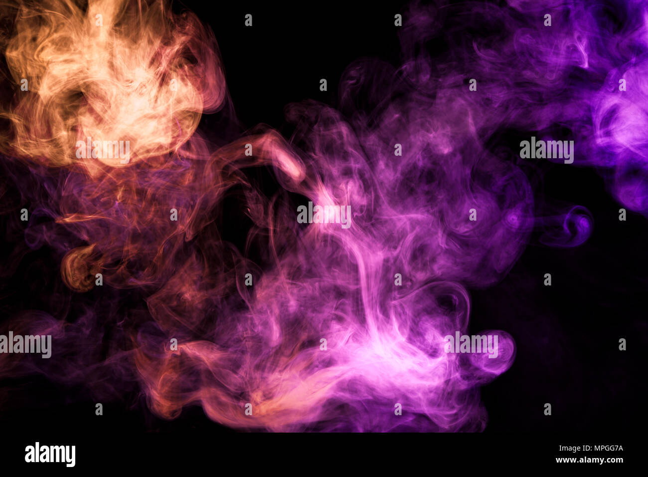 Thick colorful smoke of pink and yellow on a black isolated background ...