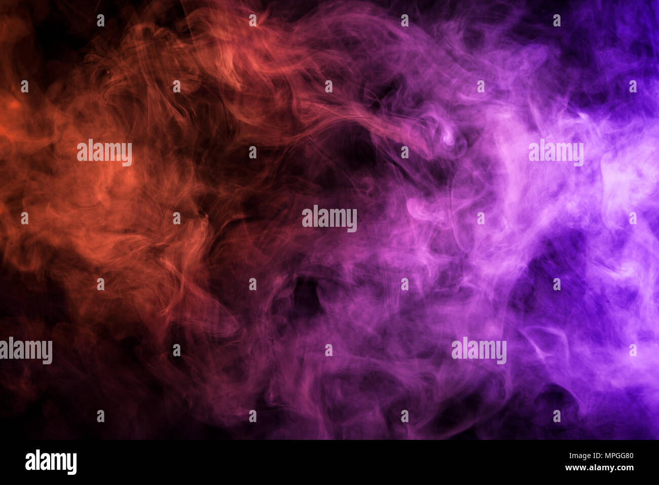 Thick colorful smoke of red and pink on a black isolated background ...