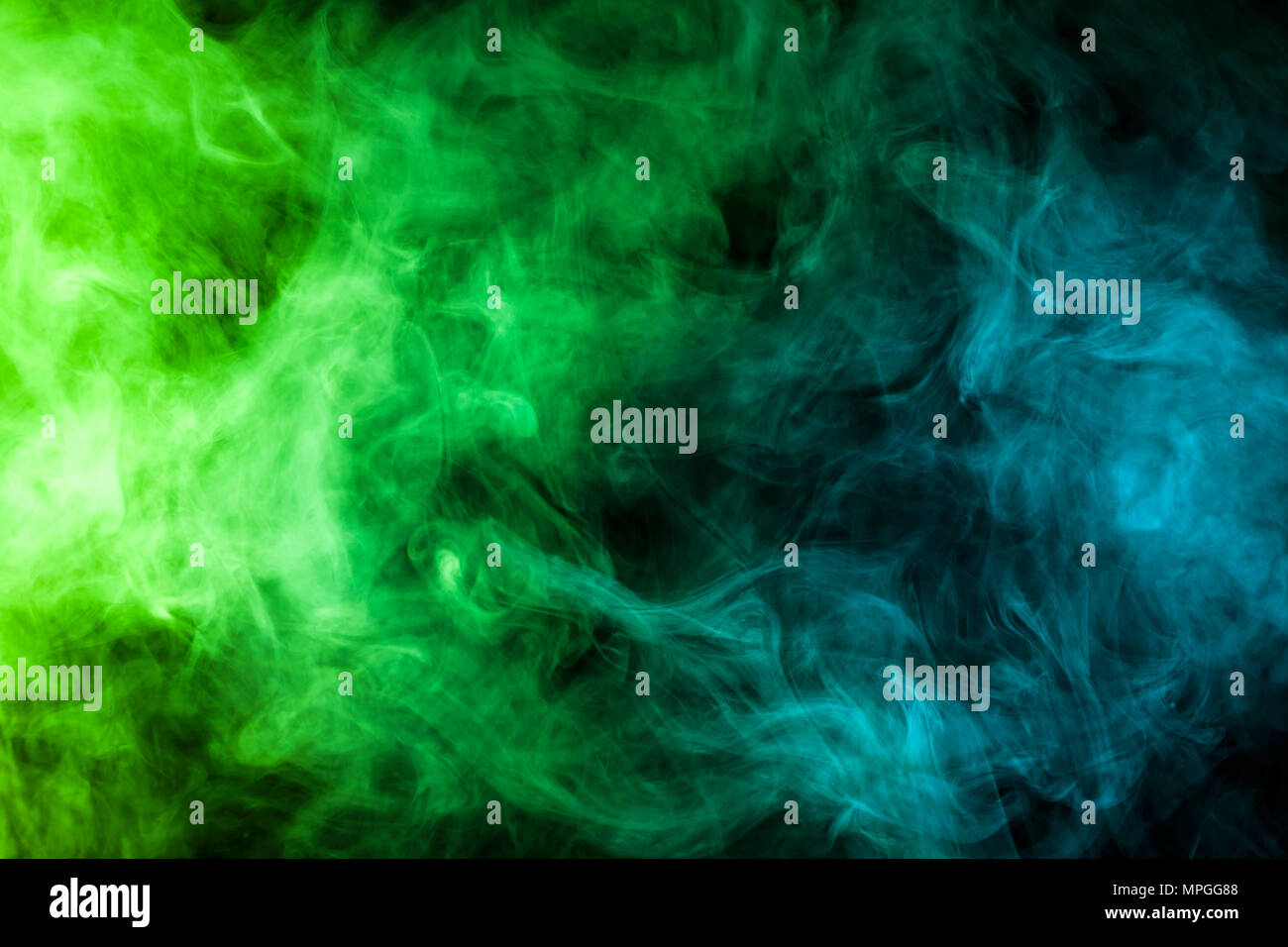 Thick colorful smoke of green and blue on a black isolated background ...
