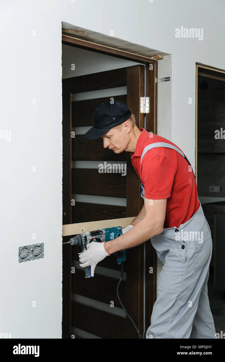Installing door unit. Workman fixing the door frame using a drill Stock ...