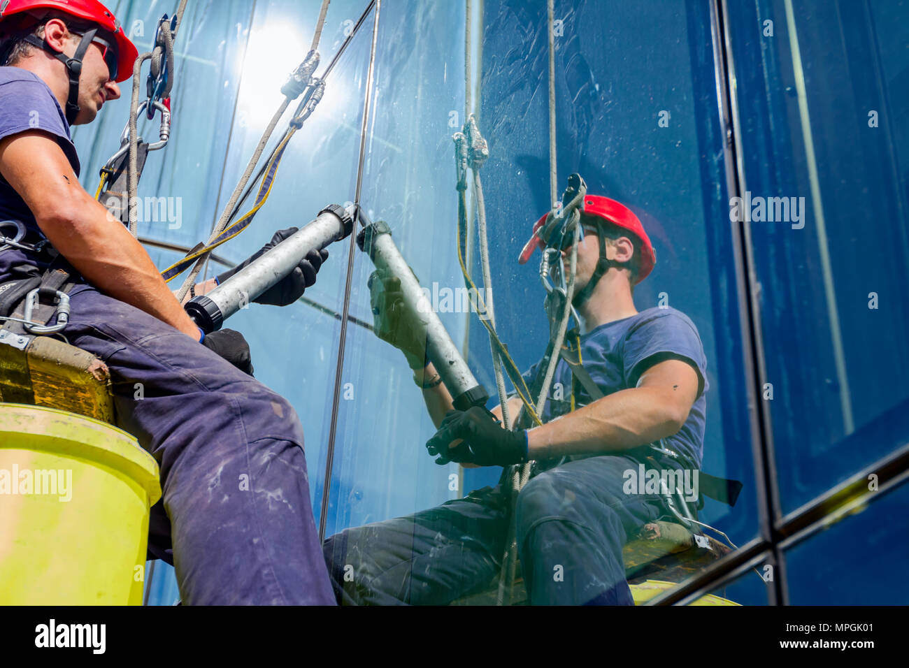 Industrial climber is applying silicone to rubber juncture among ...