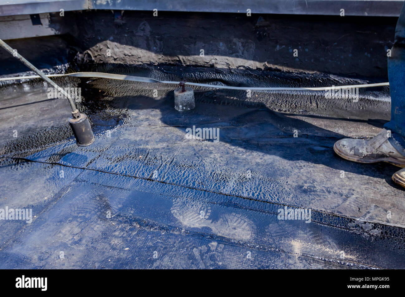 Roofing felt with heating and melting of bitumen surface by flame from ...