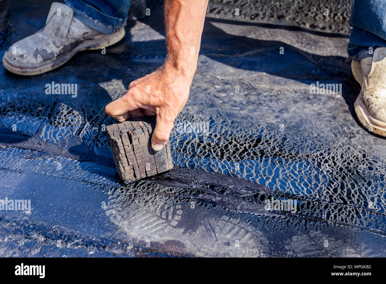 Adjust bituminous cover for roofing felt, smears melted resin with ...