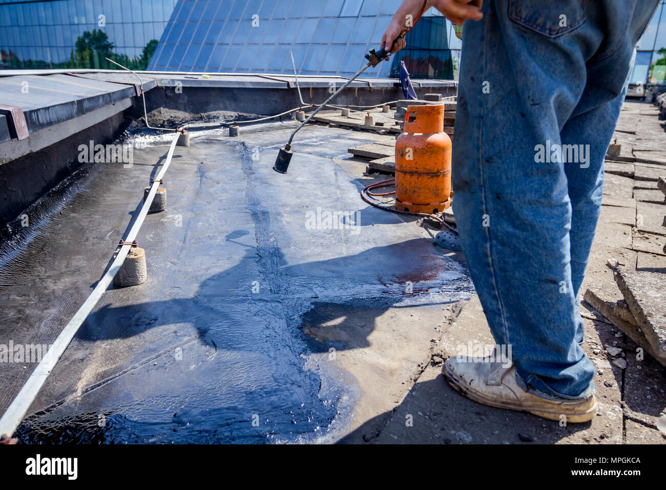 Roofing felt with heating and melting of bitumen surface by flame from ...