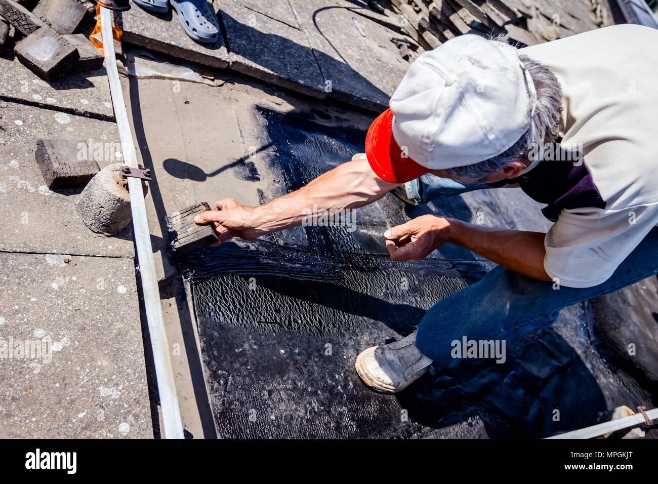 Adjust bituminous cover for roofing felt, smears melted resin with ...