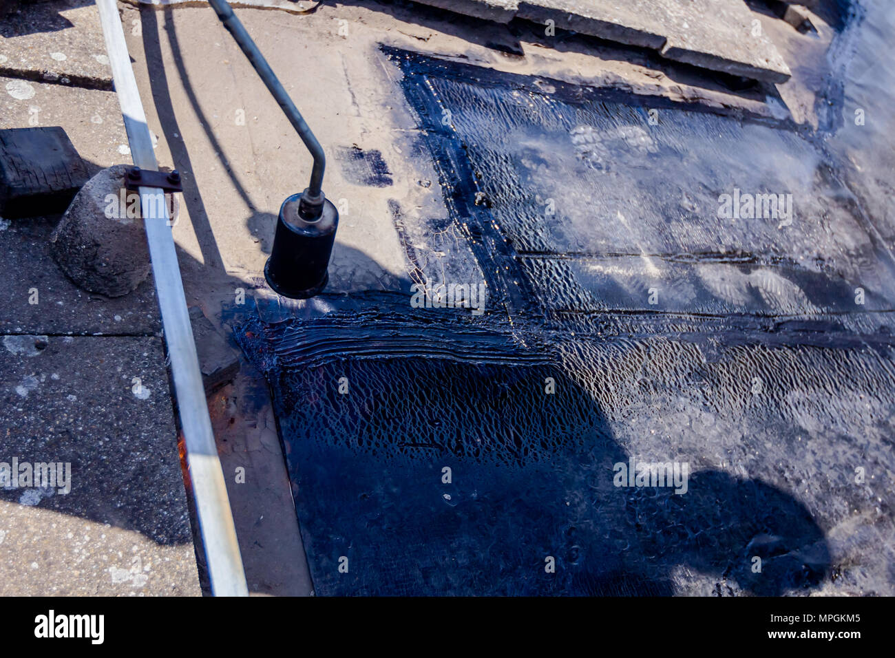 Roofing felt with heating and melting of bitumen surface by flame from ...