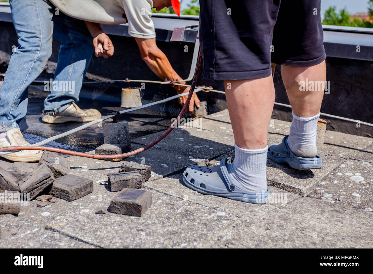 Heating and melting of bitumen surface by flame from gas torch. Worker ...