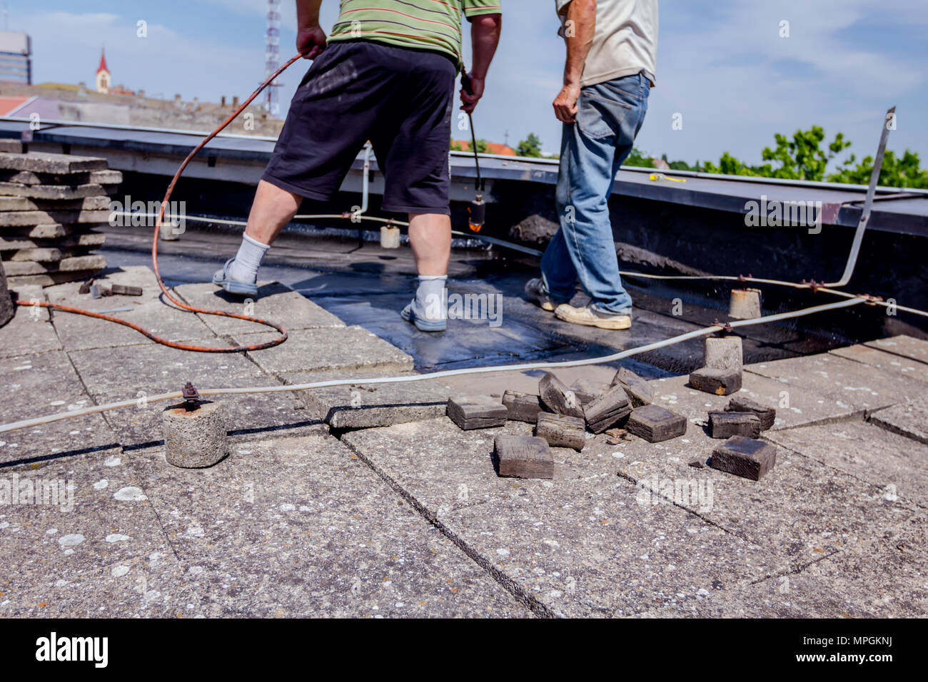 Heating and melting of bitumen surface by flame from gas torch. Worker ...