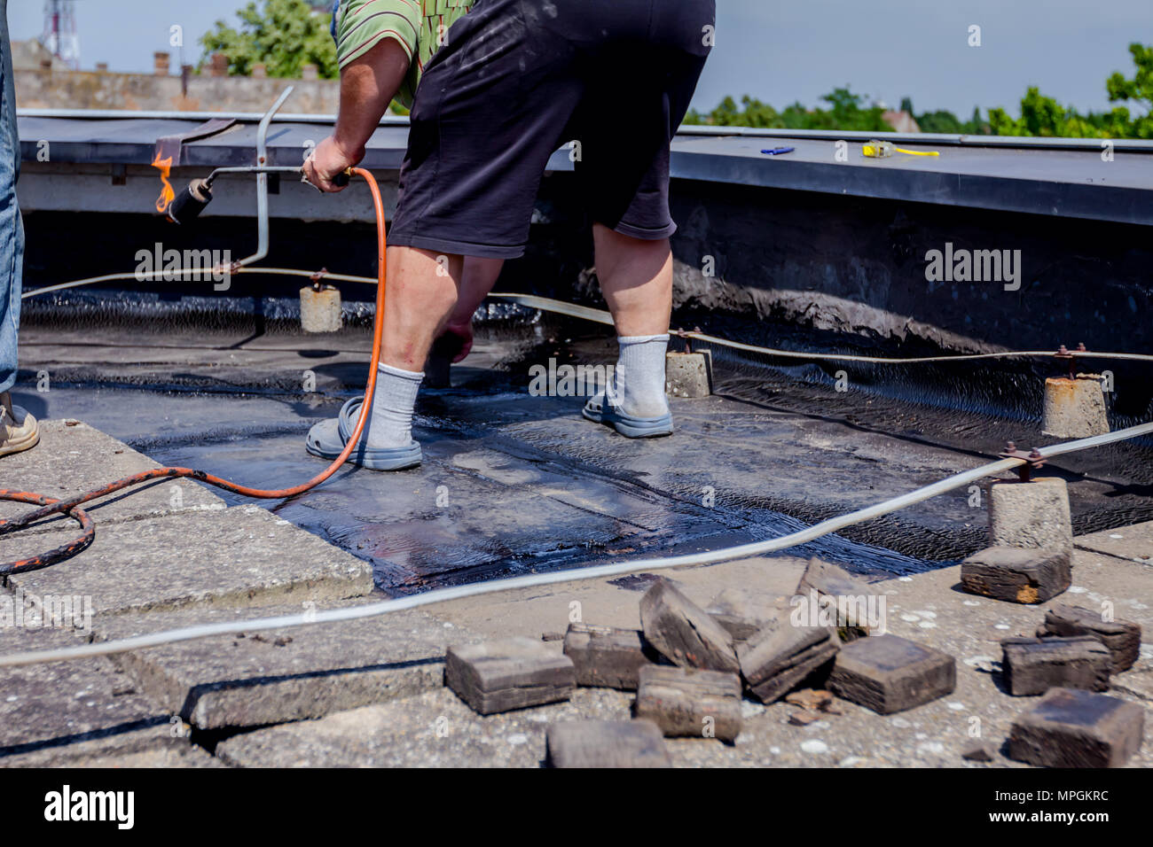 Adjust bituminous cover for roofing felt, smears melted resin with ...