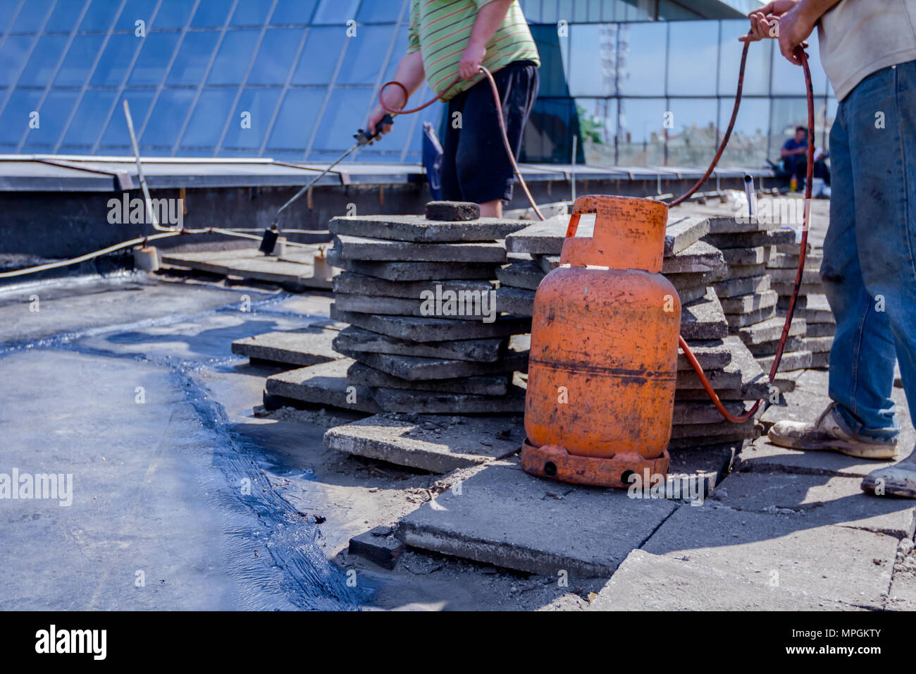 Roofing felt with heating and melting of bitumen surface by flame from ...