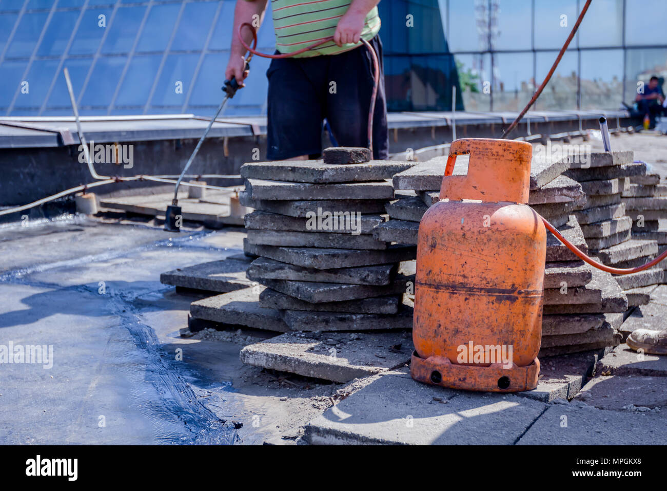 Roofing felt with heating and melting of bitumen surface by flame from ...