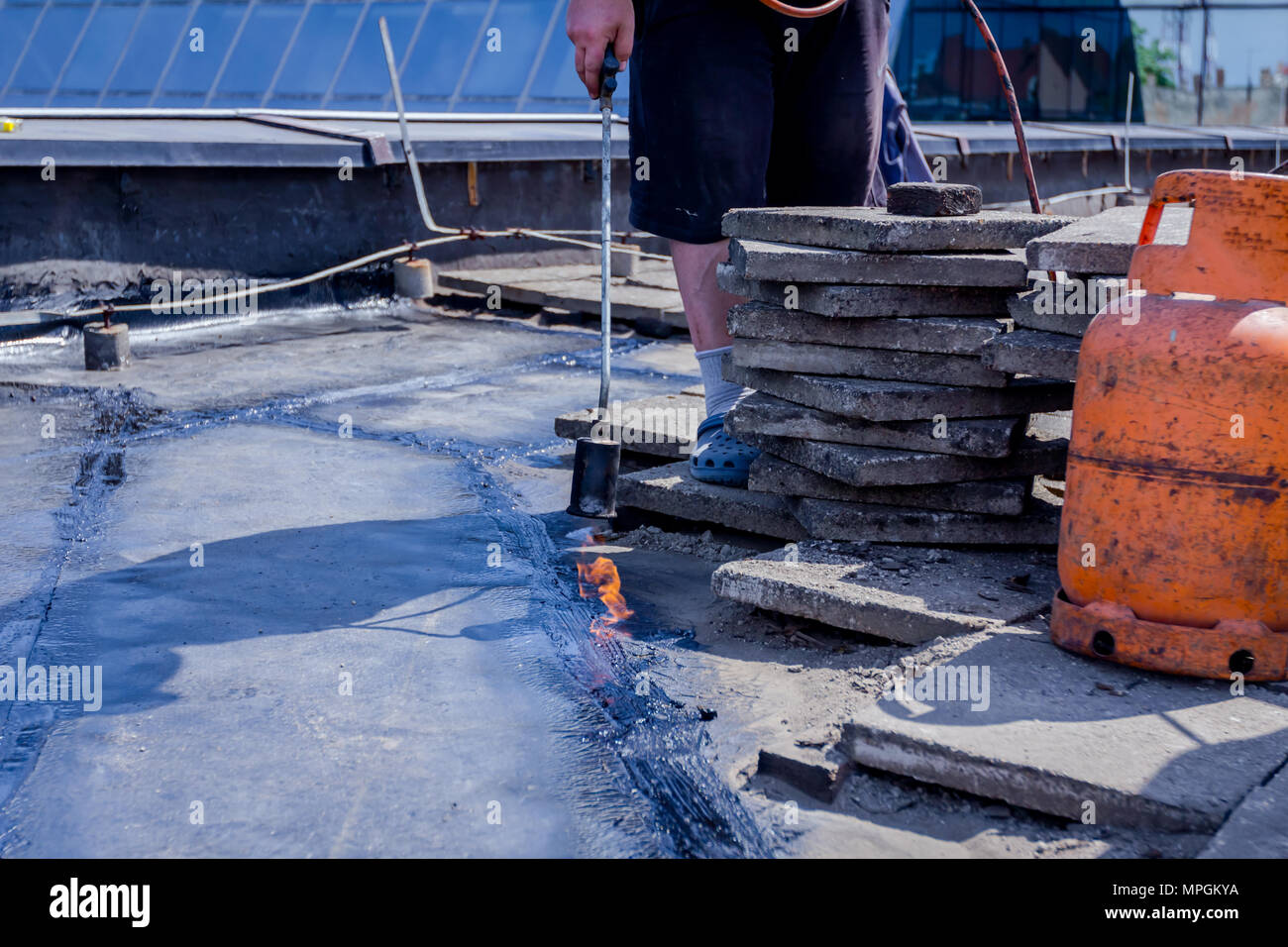 Roofing felt with heating and melting of bitumen surface by flame from ...