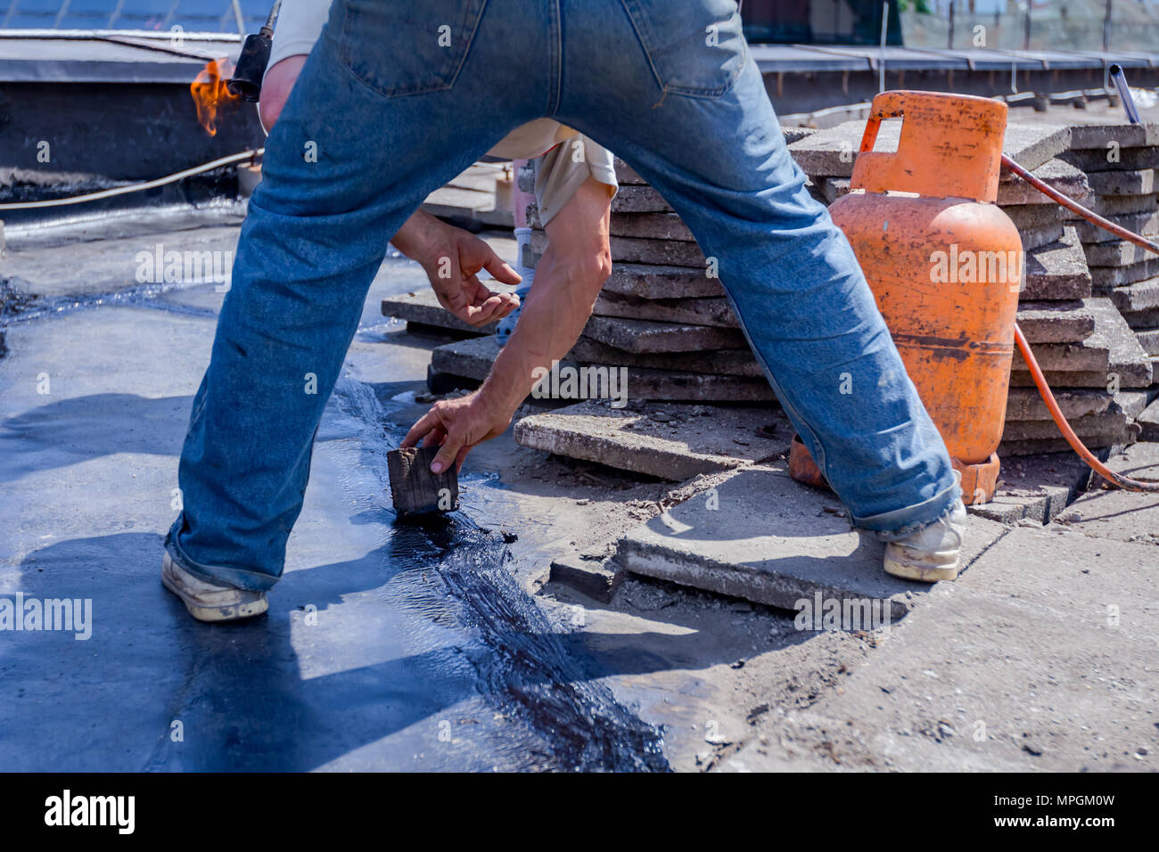 Adjust bituminous cover for roofing felt, smears melted resin with ...