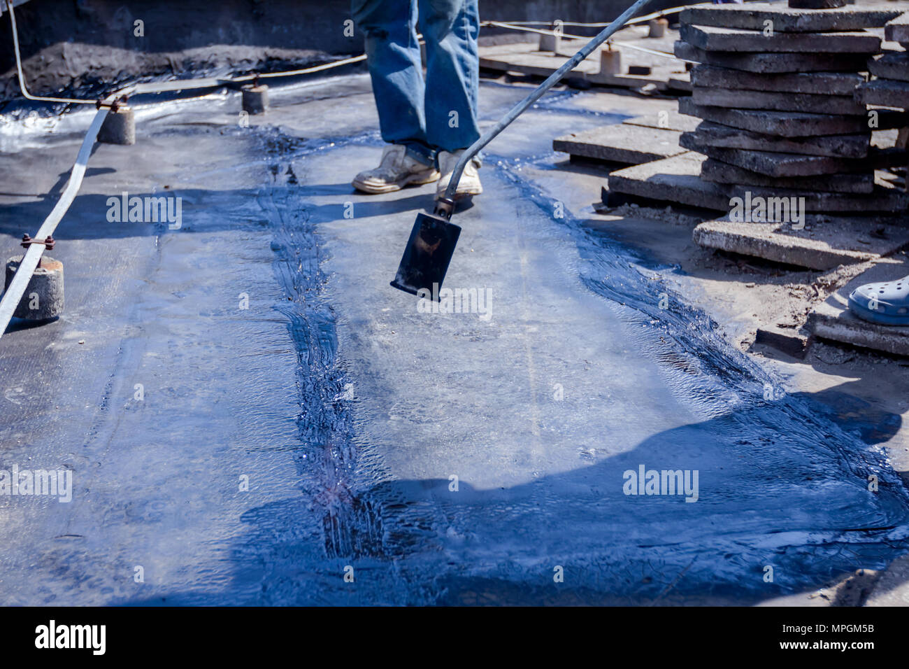 Roofing felt with heating and melting of bitumen surface by flame from ...