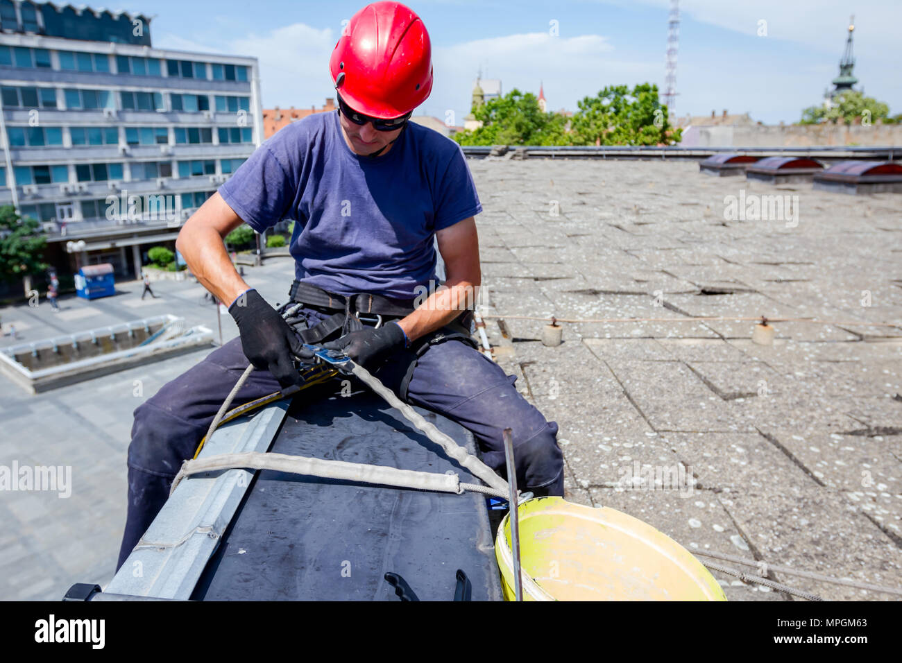 Industrial climber, alpinist, is adjusting climbing gear, preparing ...