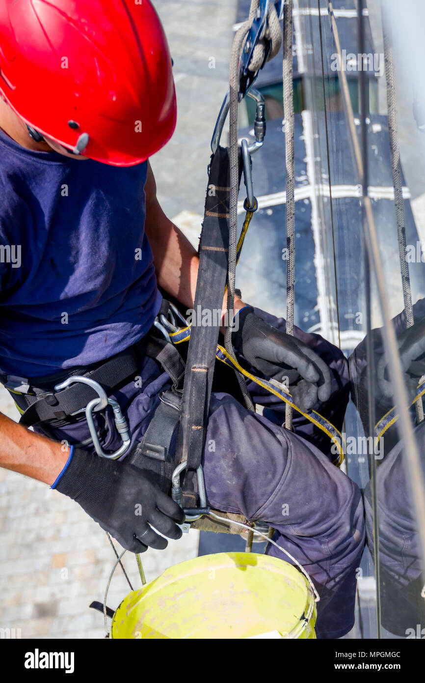 Industrial climber, alpinist, is adjusting climbing gear, preparing ...