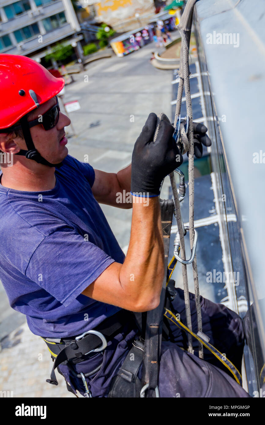 Industrial climber, alpinist, is adjusting climbing gear, preparing ...