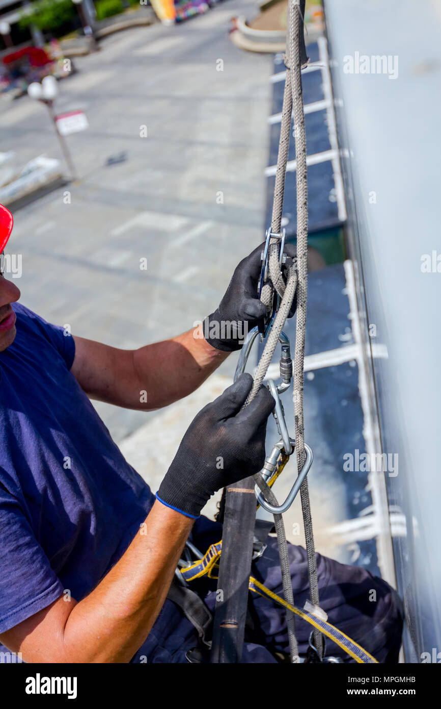 Industrial climber, alpinist, is adjusting climbing gear, preparing ...