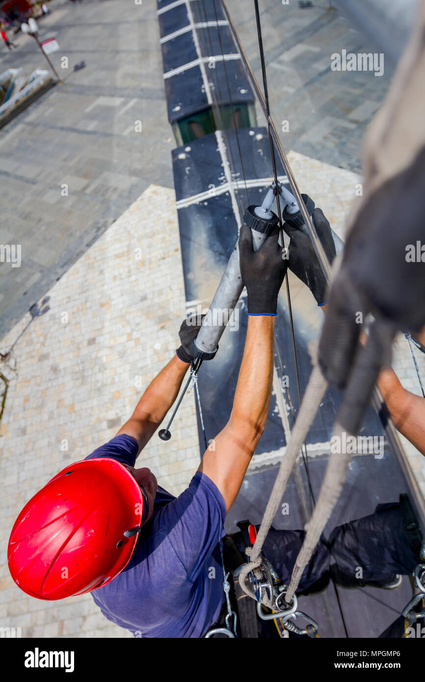 Industrial climber is applying silicone to rubber juncture among ...