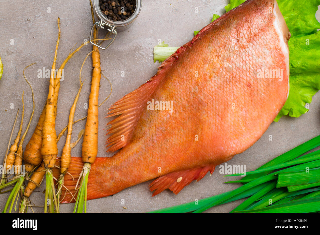 red sea perch with vegetables on the table with young carrot, spices ...