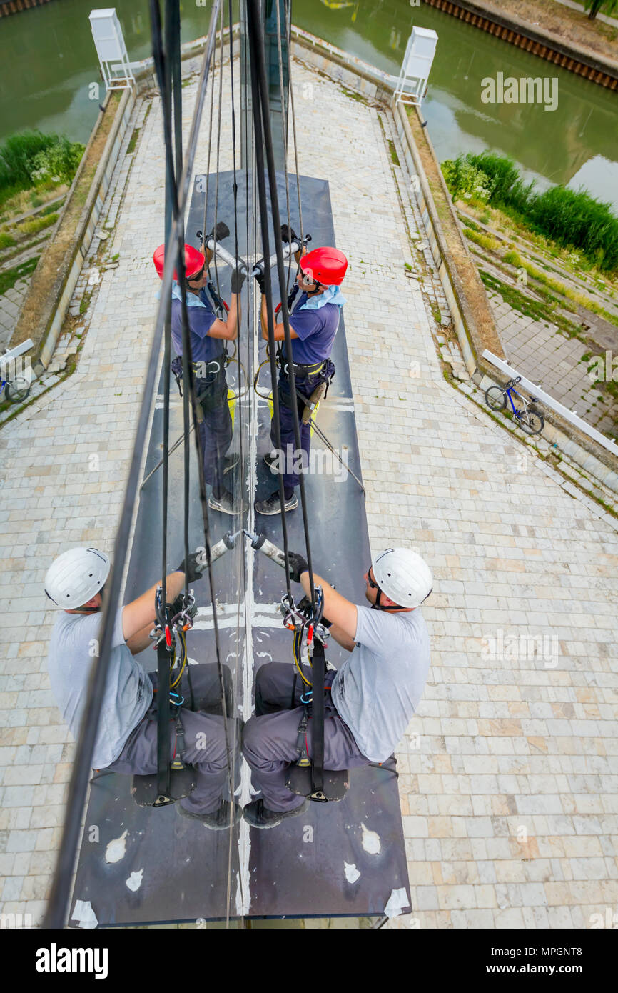 Industrial climbers are applying silicone to rubber juncture among ...