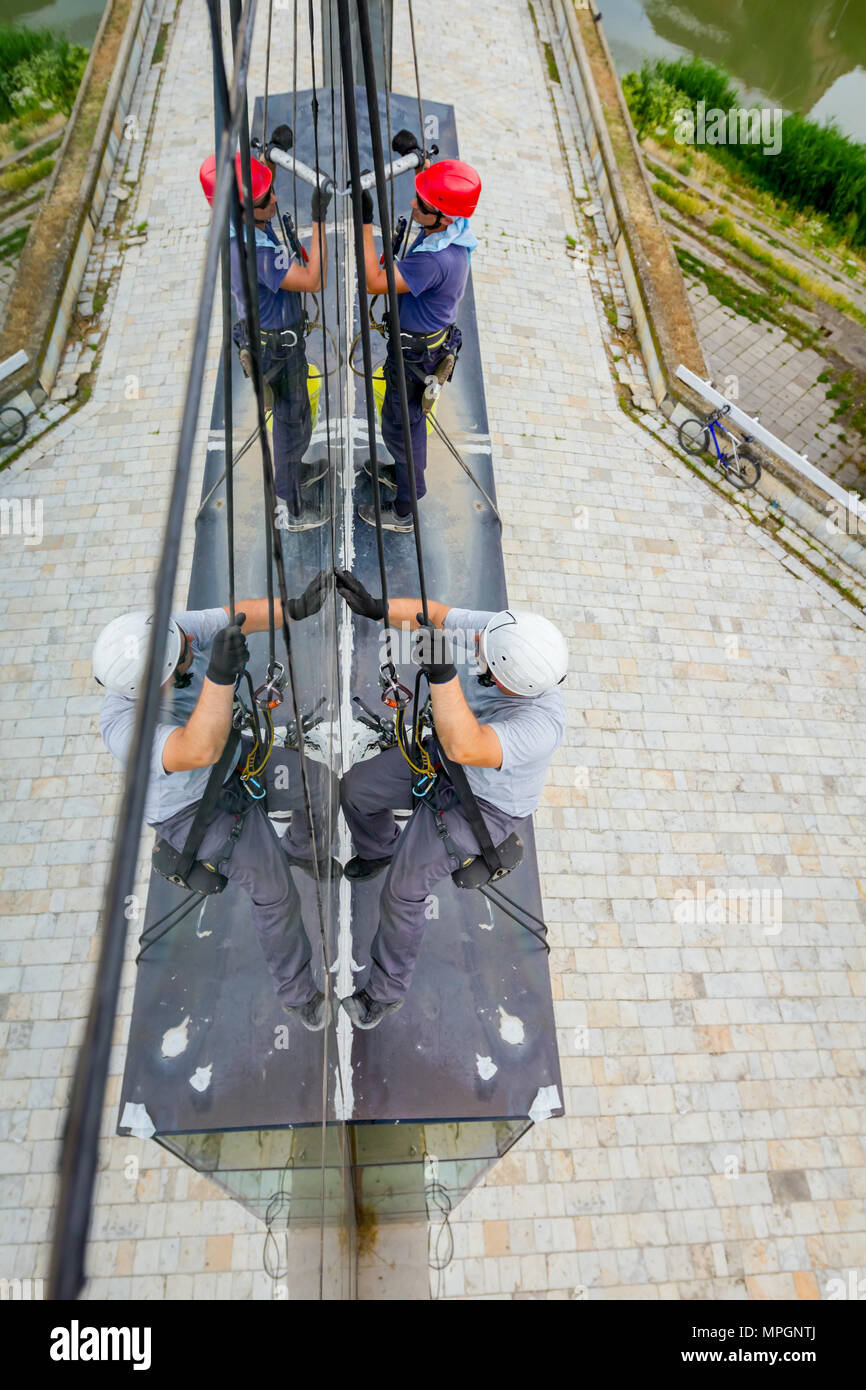 Industrial climbers are applying silicone to rubber juncture among ...