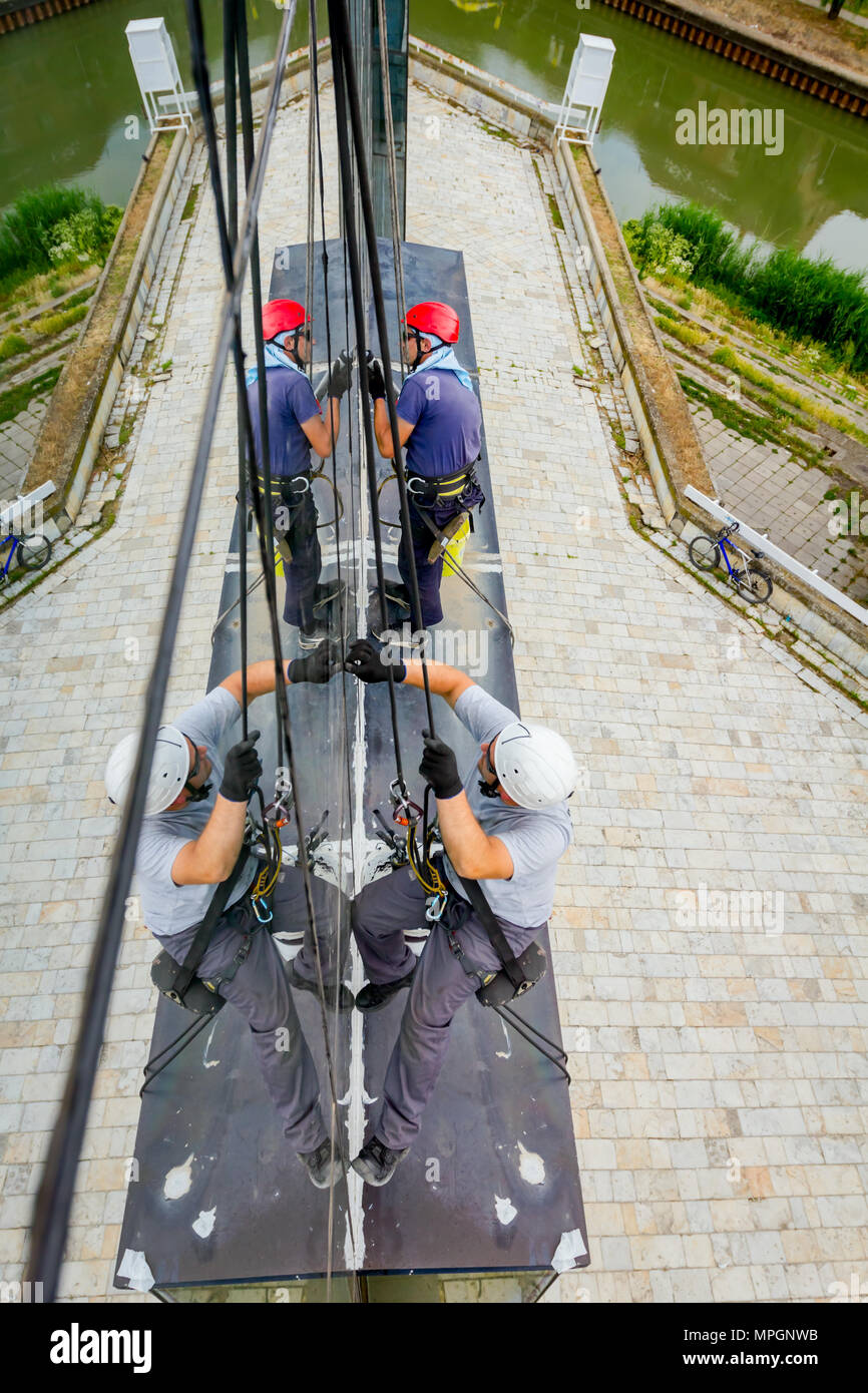 Industrial climbers are applying silicone to rubber juncture among ...