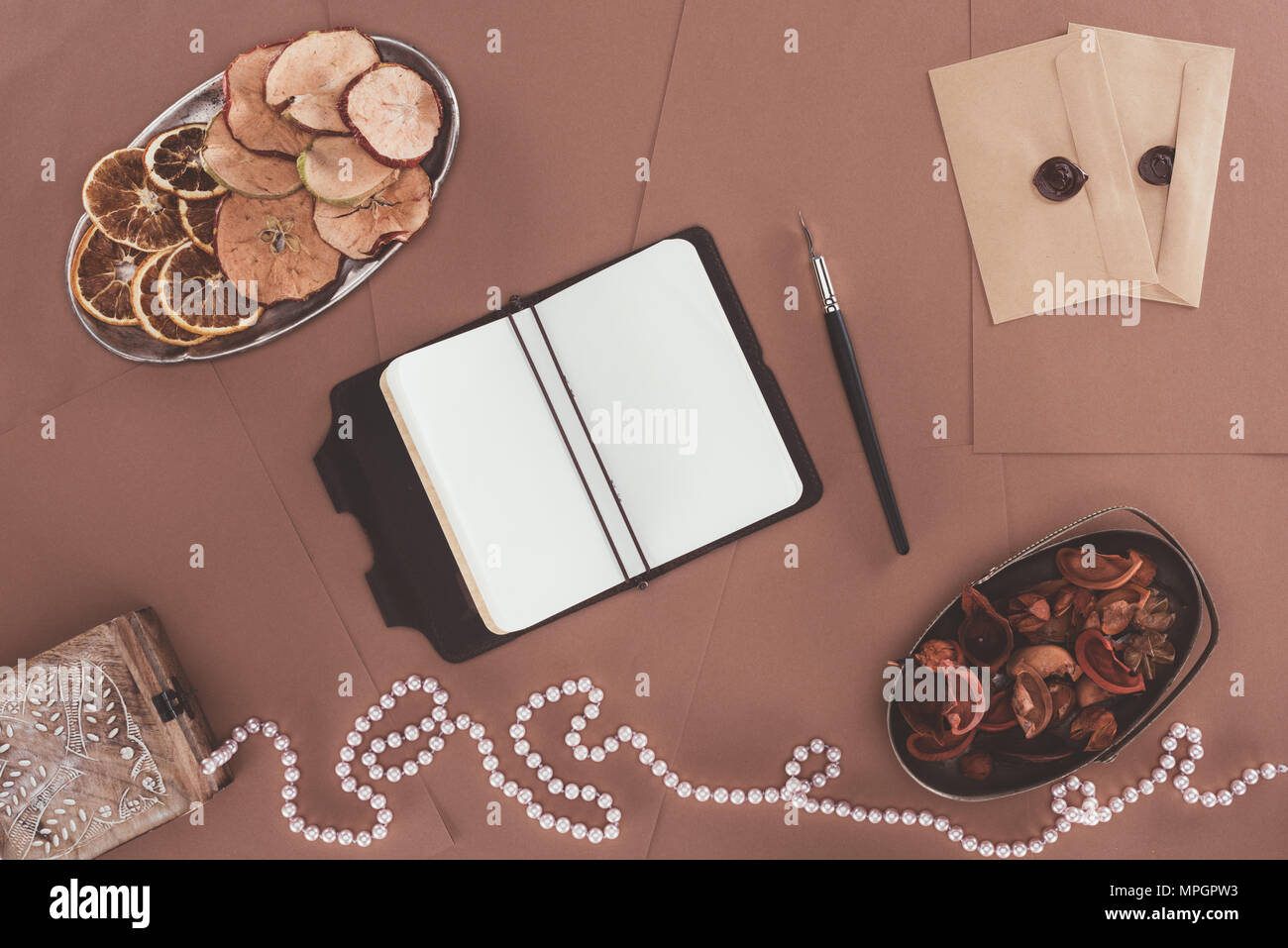 top view of notebook, jewelry box, dried fruits and envelopes over ...