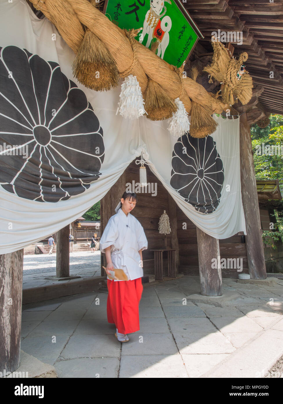 Miko shrine maiden in traditional shinto costume at Shimon main gate, Kumano Hongu Taisha, world ...