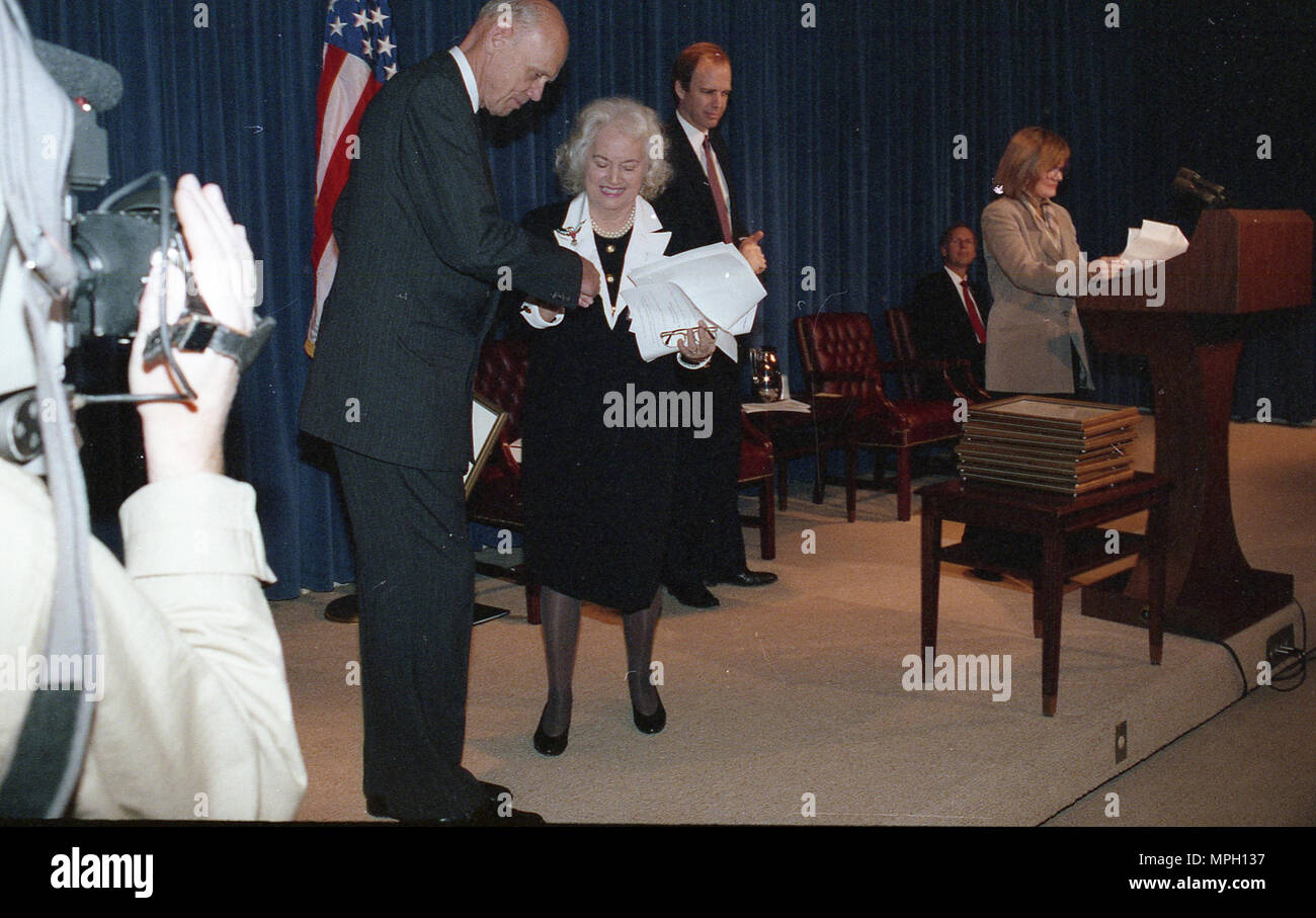 A MAN AND WOMEN AT THE PODIUM SHACKING HANDS WITH ANOTHER WOMEN AT THE ...