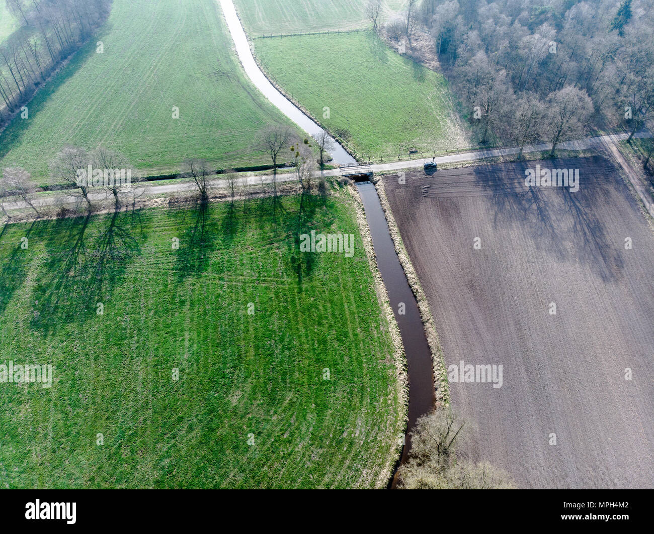 Aerial view of a stream flowing through meadows and fields under a ...