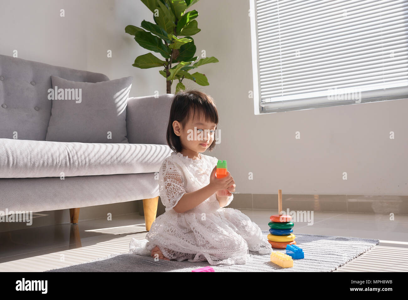 Cute little girl playing with building blocks on floor at home Stock ...