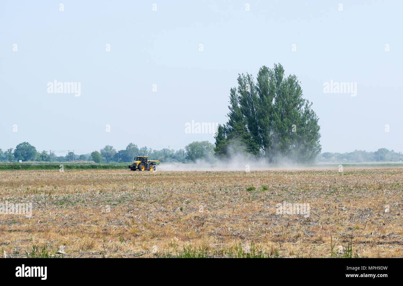 Agricultural vehicle spreading powder on fallow land Stock Photo - Alamy