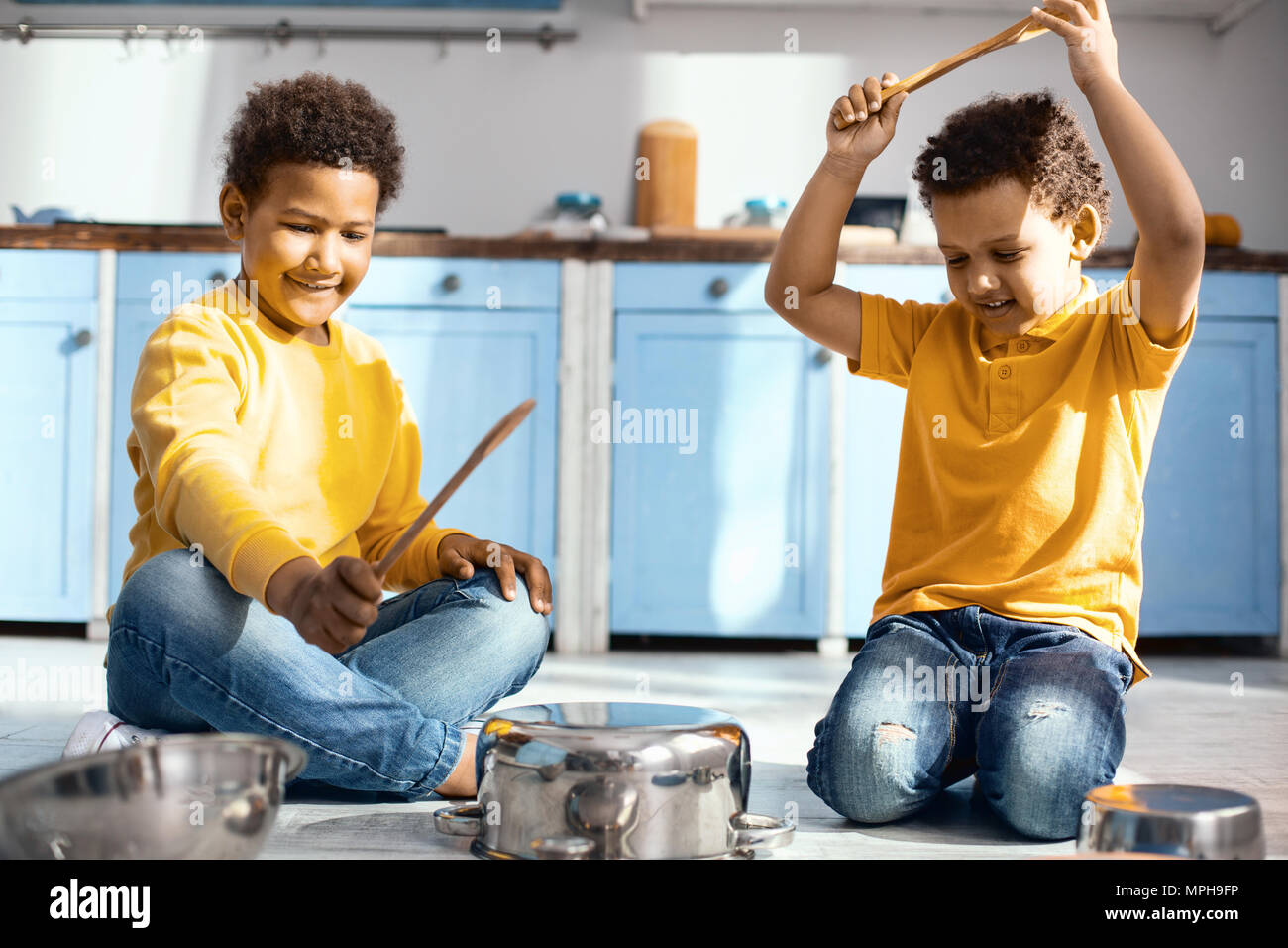 Cute little boys creating noise by drumming on saucepans Stock Photo ...
