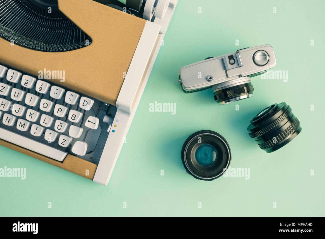 Flat lay of yellow typewriter and retro camera with lenses on table ...