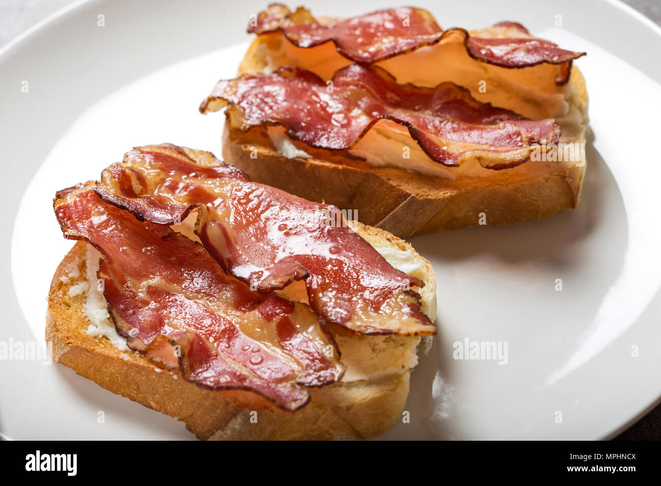 Two slices of fried bread with butter and fried bacon on plate Stock ...
