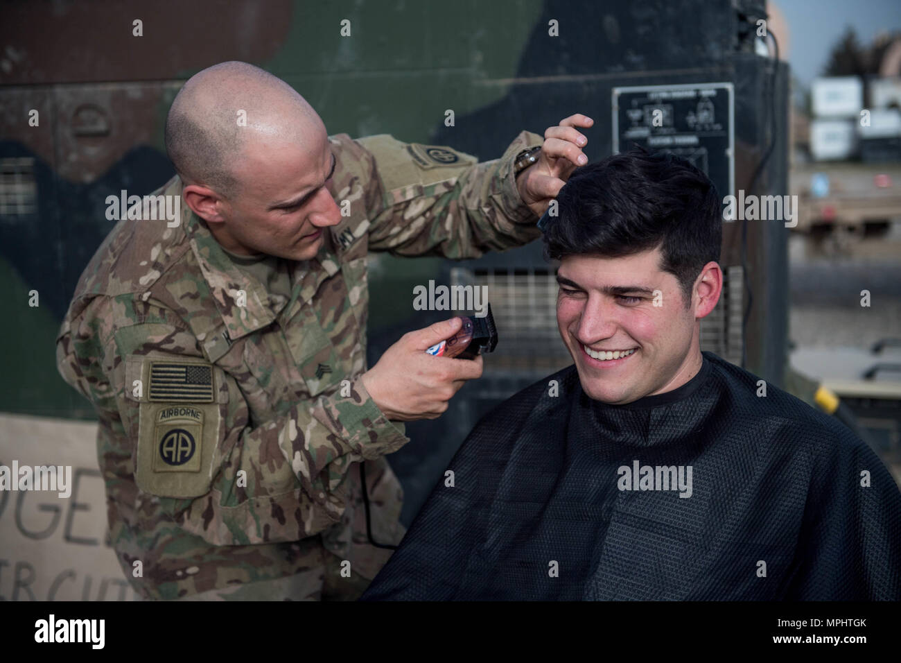 A U.S. Army first lieutenant is receiving a haircut from a sergeant ...
