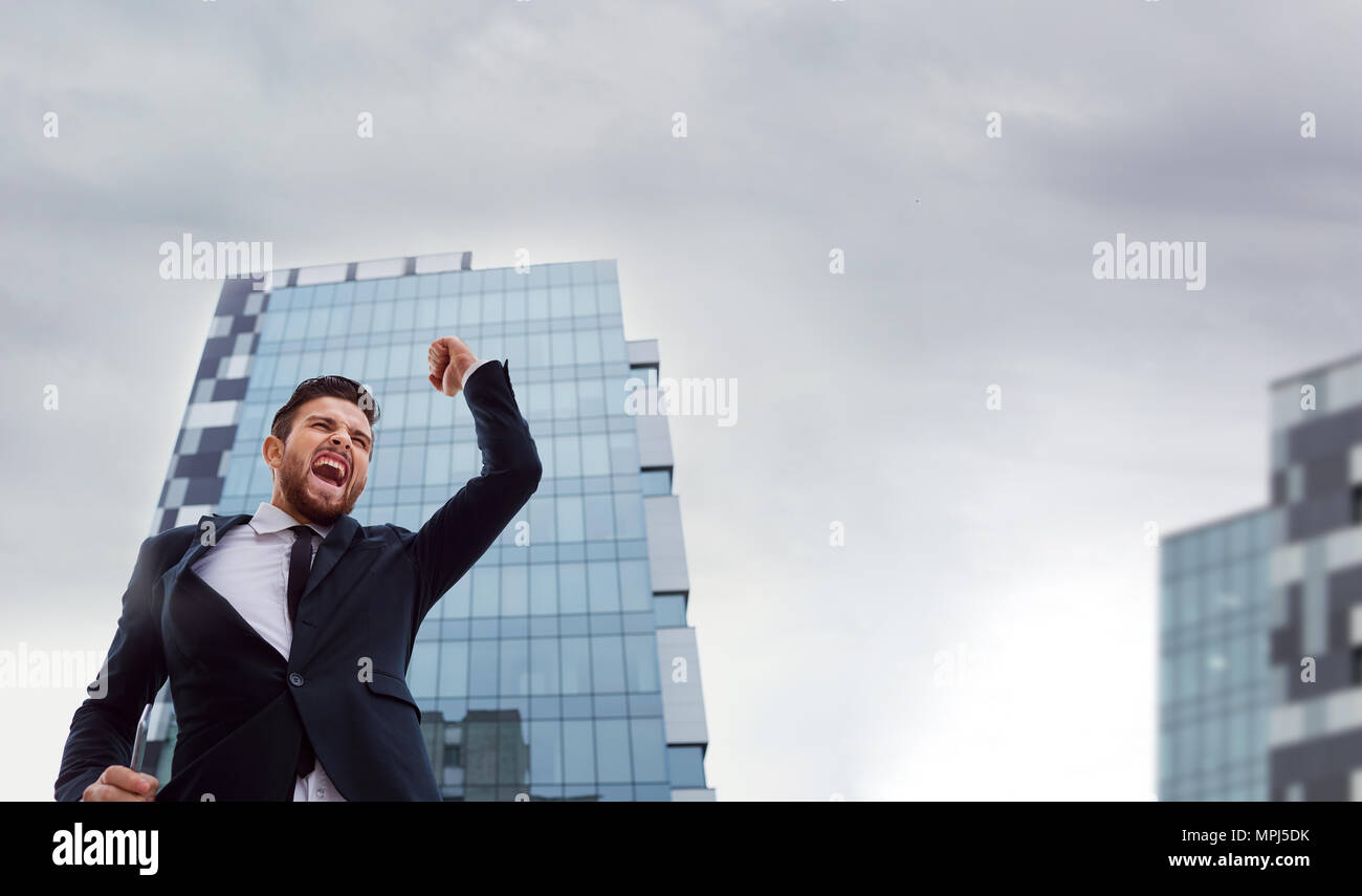 Happy businessman on a business building background Stock Photo - Alamy