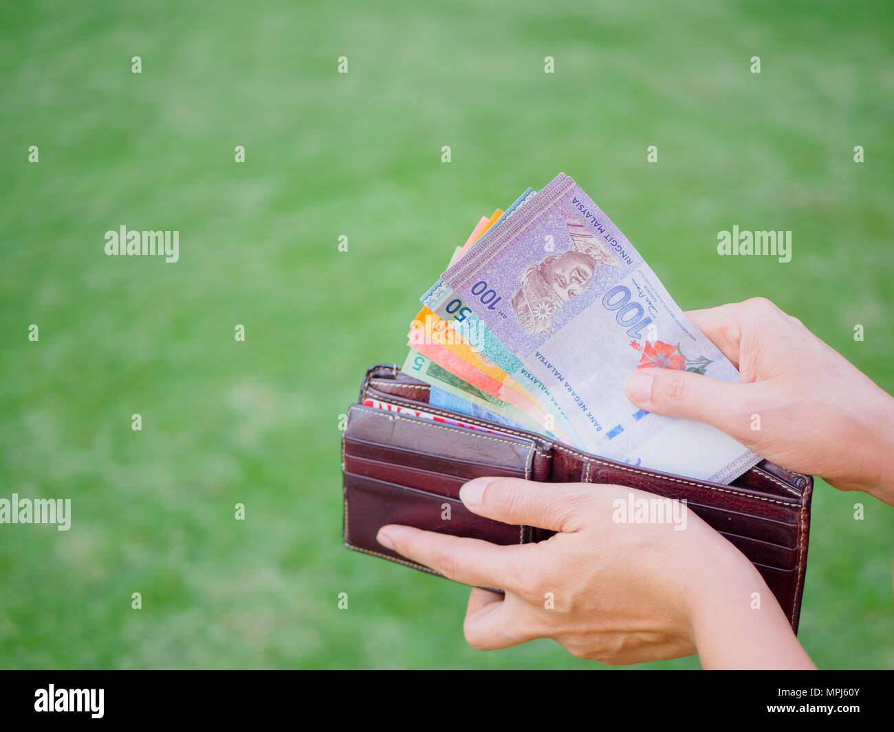 Women Hands taking out money malaysia ringgit from wallet on the green ...
