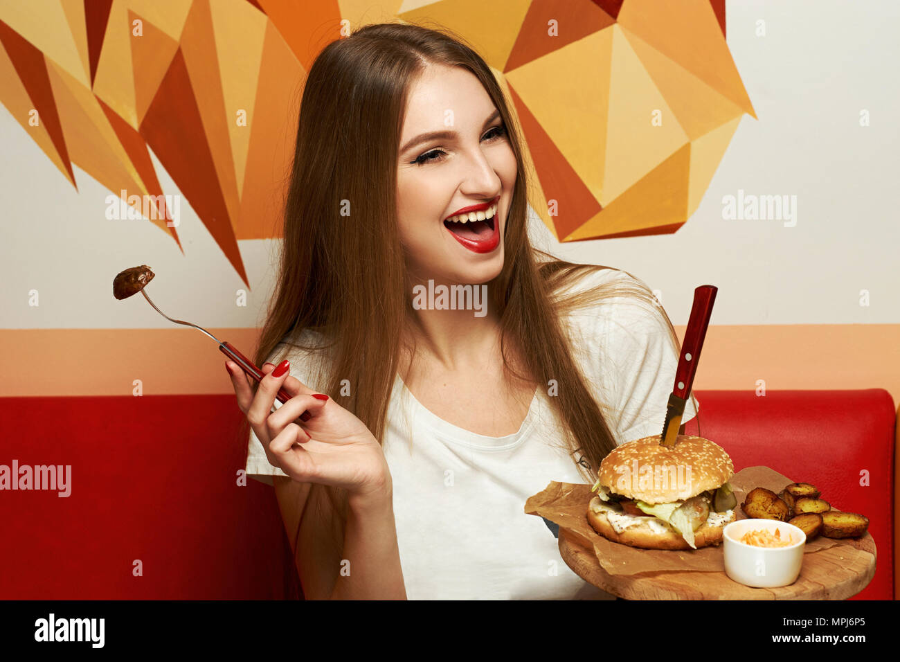 Laughing woman eating burger Stock Photo - Alamy
