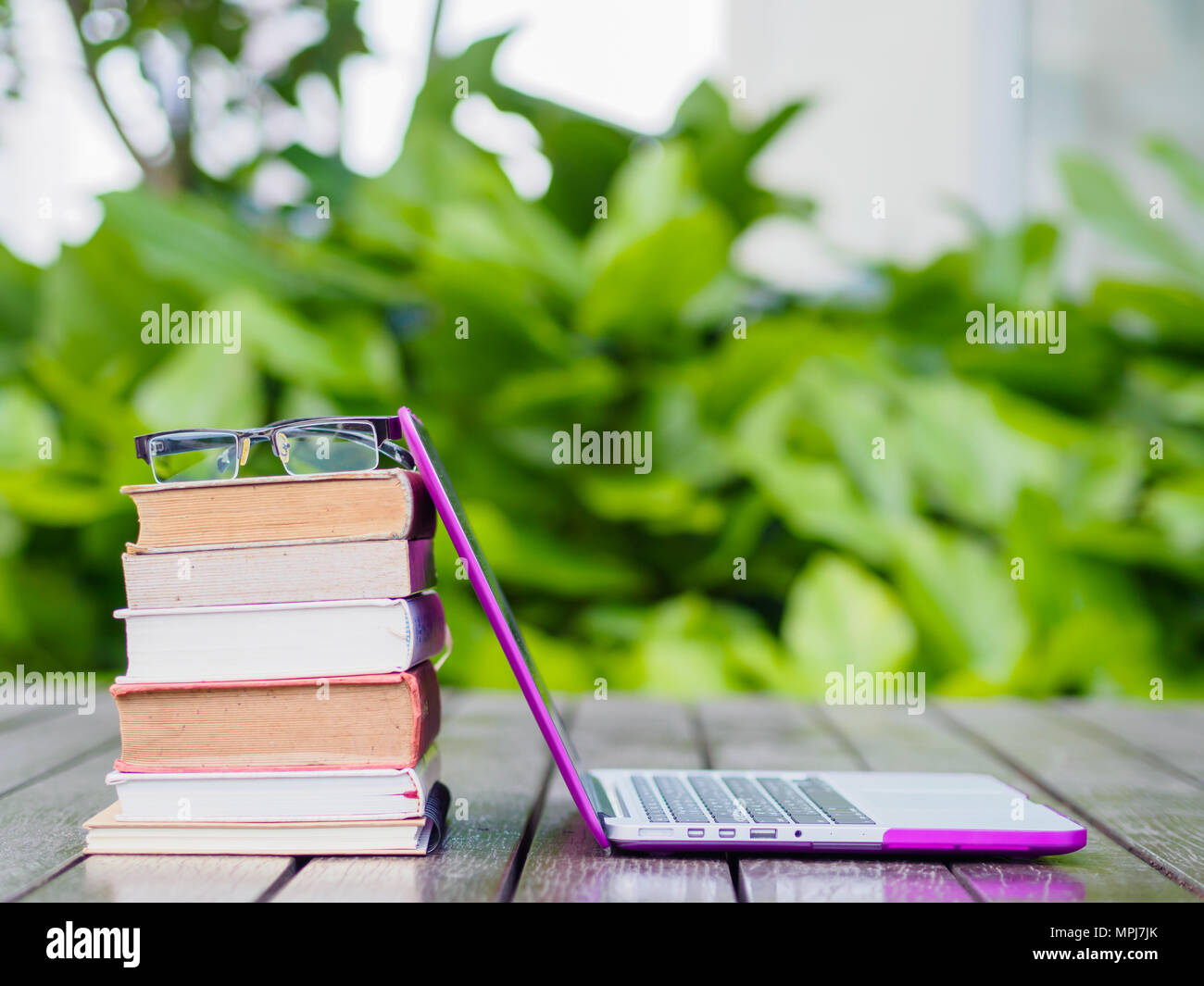 Stack of books with laptop on wood table outdoor Stock Photo - Alamy